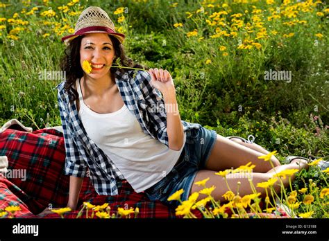 Beautiful Woman Smiling Lying In A Garden Of Flowers With A Daisy In