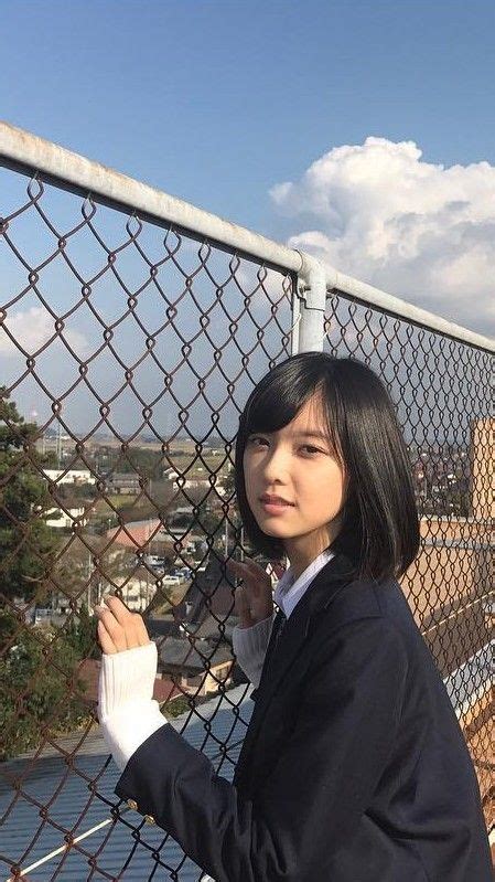 A Young Woman Standing Next To A Fence