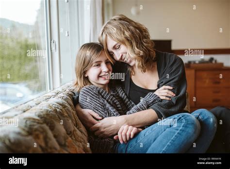Affectionate Mother And Daughter Cuddling On Living Room Sofa Stock