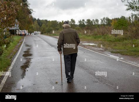 Old Man Walks Down Road Pensioner With Stick For Support Man With Leg