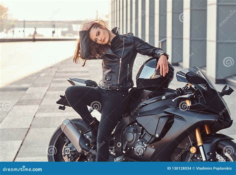 A Beautiful Biker Girl Leaning On Her Superbike Outside A Building