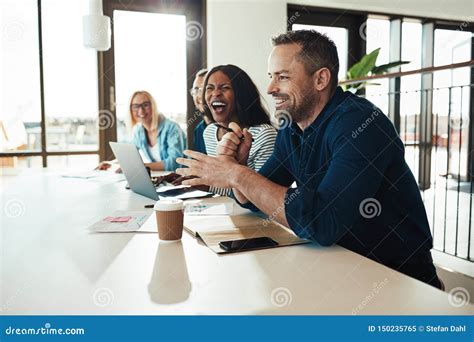 Businessman Laughing With A Group Of Office Colleagues At Work Stock