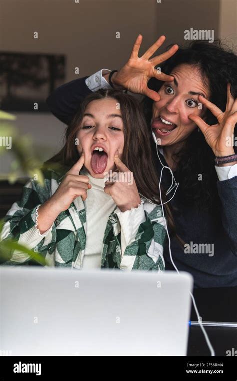 Playful Mother With Daughter Making Faces In Front Of Digital Tablet At