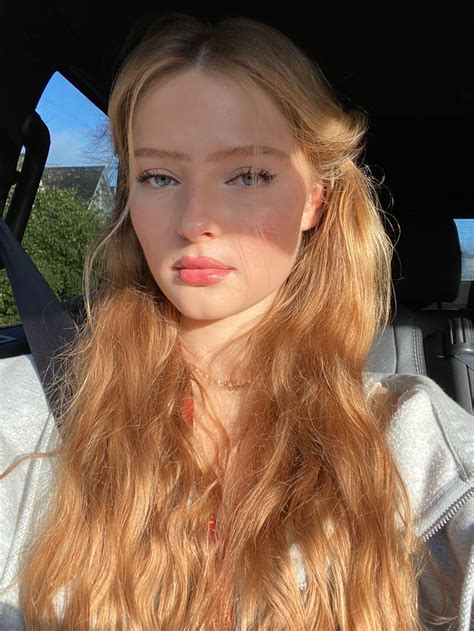 A Woman With Long Red Hair Sitting In The Back Seat Of A Car Looking At