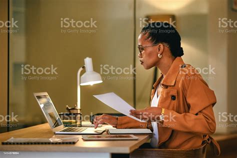 심각한 흑인 여성이 노트북으로 작업하고 사무실의 책상에서 문서를 보고 있습니다 젊은 생각 아프리카 계 미국인 재무 분석가는