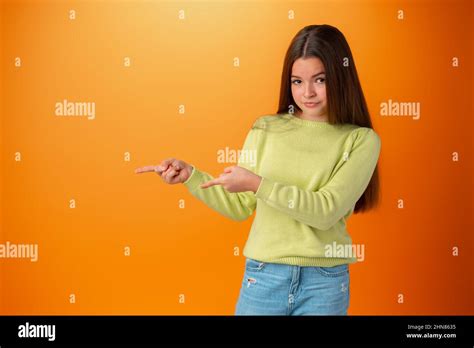 Cute Teen Girl Pointing On Copy Space Behing Her Back Against Orange