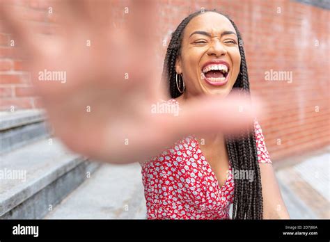 Woman Showing Stop Gesture While Sitting On Staircase In City Stock