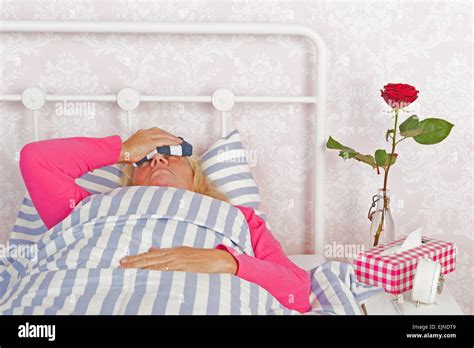 Sick Woman In Pink Pajama With Headache Tissues And A Rose Lying In