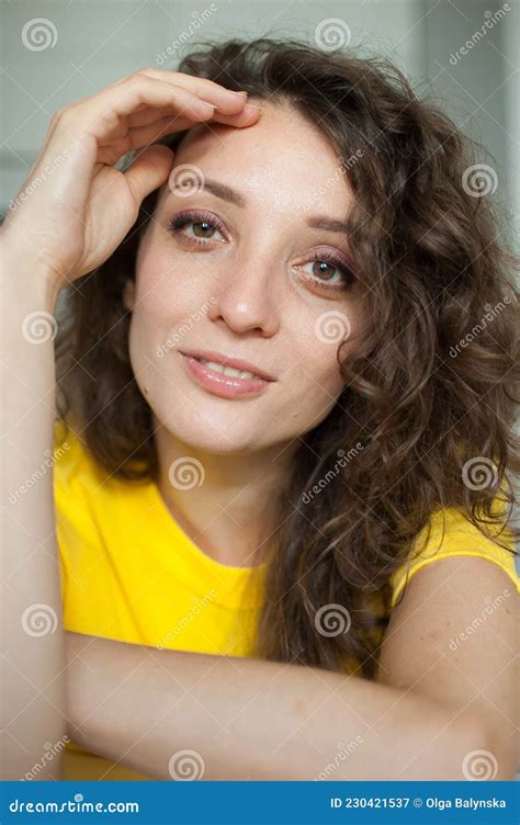 Beautiful Curly Girl In Yellow T Shirt Is Looking At The Camera At Home