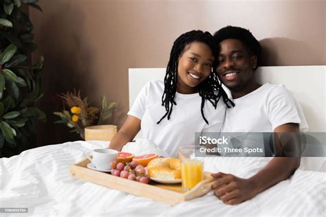 Happy Delighted African American Black Couple Lying In Bed Holding Tray