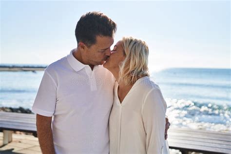 Middle Age Man And Woman Couple Hugging Each Other And Kissing Standing