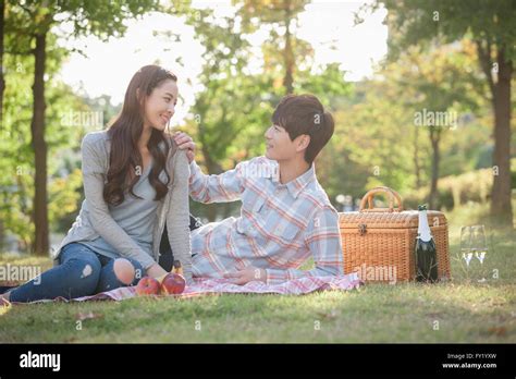 Couple On A Picnic And Looking At Each Other With A Smile At Park Stock