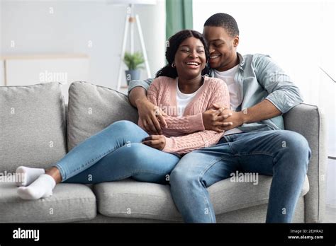 Joyful African American Couple Hugging And Laughing Home Interior