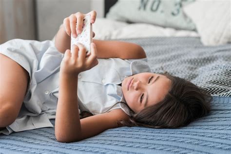 Fille Allongée Sur Le Lit à Laide Dun Téléphone Intelligent Photo