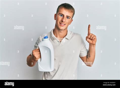 Young Caucasian Man Holding Detergent Bottle Surprised With An Idea Or