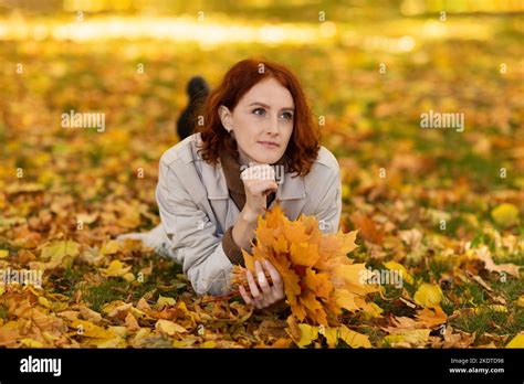 Serious Dreaming Caucasian Millennial Woman With Red Hair In Raincoat