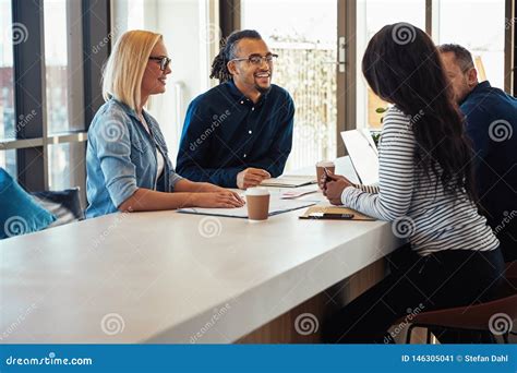 Group Of Laughing Coworkers High Fiving During An Office Meeting Stock