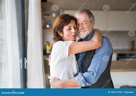 Affectionate Senior Couple In Love Standing Indoors At Home Hugging