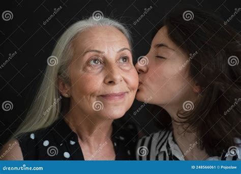 Portrait Of Senior Grandmother With Her Granddaughter Kissing Her Over