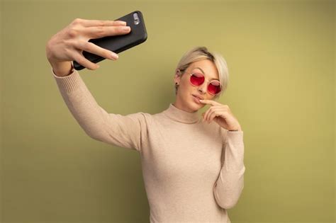 Segura Joven Rubia Con Gafas De Sol Poniendo El Dedo En El Labio