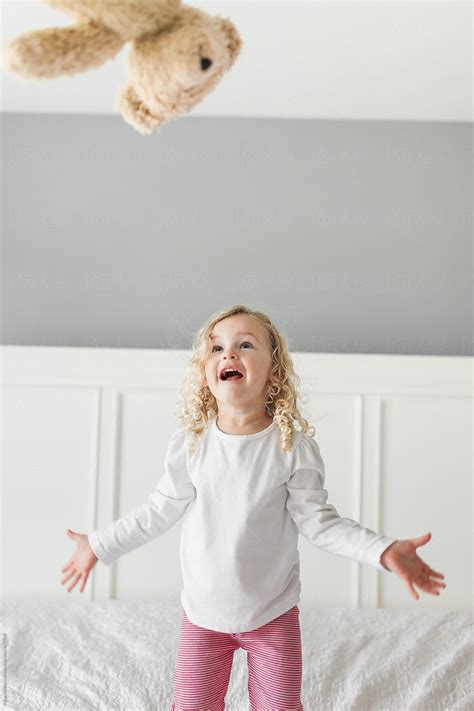 Happy Young Girl Wearing Red And White Striped Pajamas Throwing Teddy