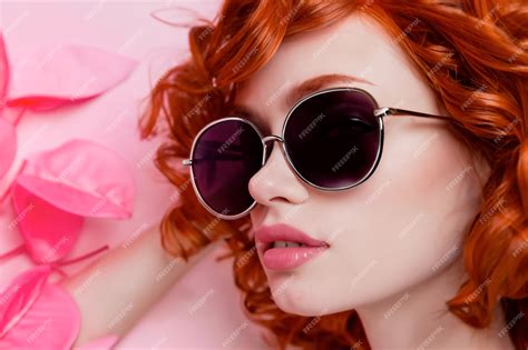 Premium Ai Image A Woman With Red Hair Wearing Sunglasses And A Pink