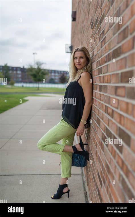 Portrait Of A Woman Looking At The Camera As She Leans Against A Brick