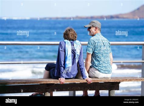 Couple Of Old Retired Seniors Man And Woman Siting At A Bench Watching