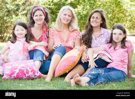 Portrait Of Two Mature Women Sitting In A Park With Their Daughters And