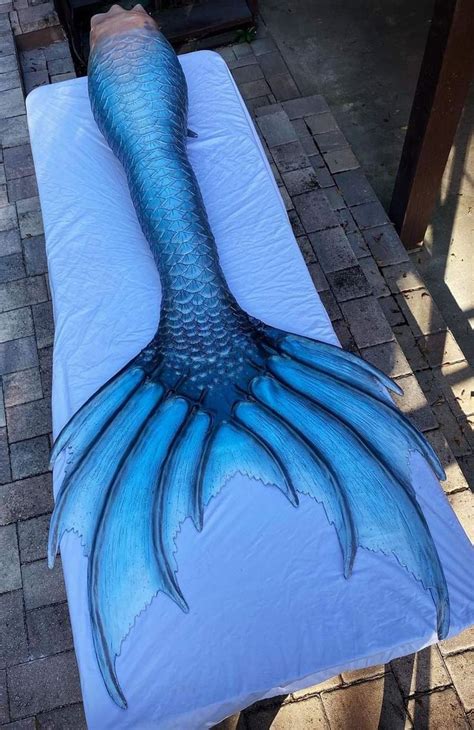 A Large Blue Mermaid Tail Laying On Top Of A White Sheet Covered