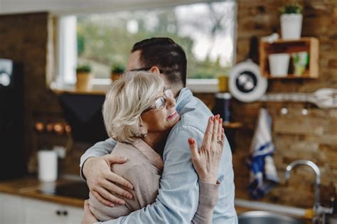 Free Photo Happy Senior Mother And Her Adult Son Embracing In The Kitchen