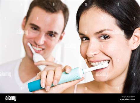 A Beautiful Interracial Couple In The Bathroom Brushing Teeth Stock