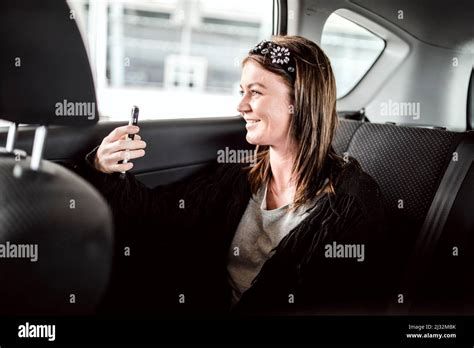 A Taxi Or Uber Passenger Talking Through The Phone On The Car Back Seat
