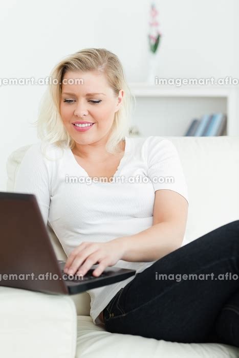 Casual Woman Sitting On The Sofa Using A Laptop In A Living Roomの写真素材