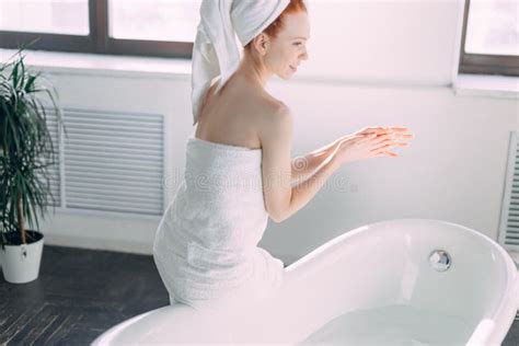 Smiling Woman Sitting On Bathtub Edge Running The Bath Testing Water
