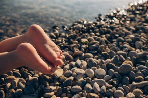 Premium Photo A Womans Bare Feet Sits On A Pebble Beach