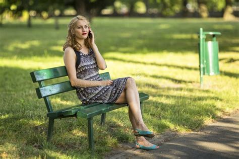 Frau Die Am Handy Sitzt Auf Einer Bank Im Park Spricht Stockbild