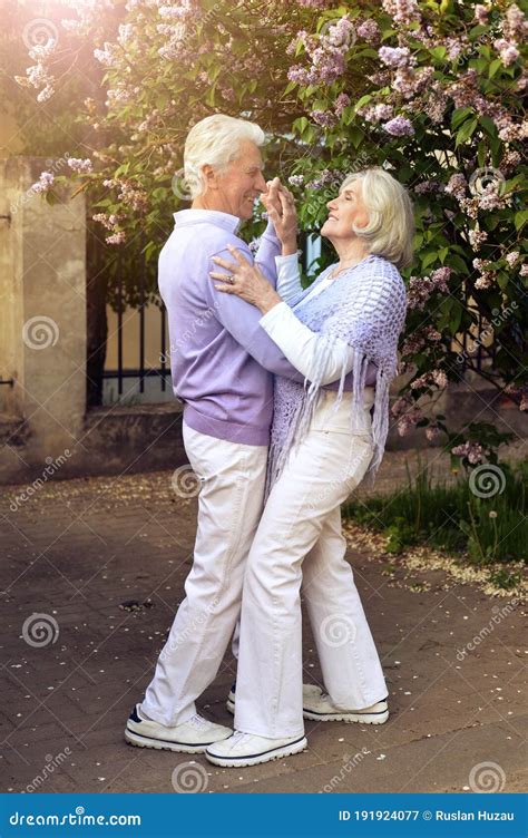 Beautiful Senior Couple Dancing In The Park By Lilacs Stock Image
