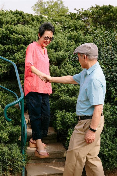 Man Helping Woman Down Garden Steps By Stocksy Contributor Curtis