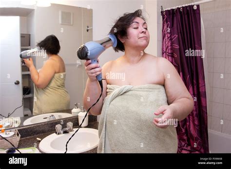 Drying Hair Wrapped In A Towel A Woman Stands In Her Bathroom