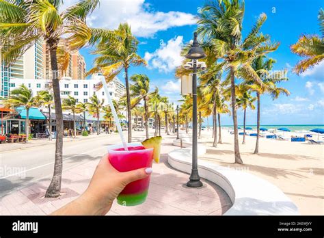 Seafront Beach Promenade With Hand Holding Cocktail And Palm Trees On