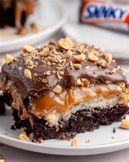 Snickers Cake 🍫🥜🍰 This rich and indulgent Snickers-style cake is layered with moist Devil’s Food cake, gooey caramel, melty chocolate chips, and crunchy peanuts. Finished with creamy milk chocolate frosting, caramel drizzle, and extra peanuts, it’s decadent, nostalgic, and perfect for celebrations or serious chocolate cravings. Ingredients: 15.25 oz boxed Devil’s Food Cake mix (Duncan Hines) 1 cup evaporated milk, divided (¾ cup for cake, ¼ cup for caramel) ½ cup canola oil 2 large eggs, room