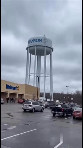 A full-size city water tower tipped over and collapsed directly onto a Branson Walmart, destroying the building on impact before rupturing and sending water surging across the parking lot. Video shows the structure crushed beneath the tower as cars were swamped and people ran from the scene. | Branson Area Breaking News