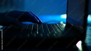 Typing on the laptop keyboard in the dark room, office. Close up, point to fingers.