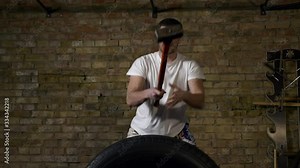 Boxer Fighter Hammering Power Workout. Professional Athlete Intensive Working out Sledgehammer on Tyre. Exercise Warming up Training in Eastern Asia Style Studio. 2x Slow motion - 0.5 speed 60 FPS