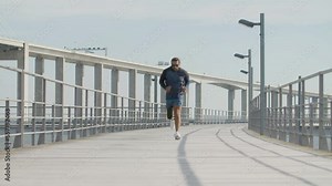 Athlete with prosthetic leg running at fast pace outdoor. Front view of focused man in sunglasses and sportswear sprinting, pushing himself, perfecting skills. Sport, cardio workout concept