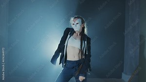 Fit girl in face mask dancing contemporary against blue smoke. Faceless young woman performing modern dance. Professional female dancer moves her body rhythmically at night party