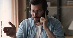 Attractive confident businessman in glasses sit indoor talk to client on cellphone close up. Distant communication using mobile virtual network operator, modern tech and connection, phone call concept