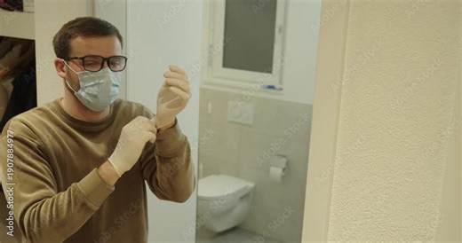 Man putting on a face mask and disposable gloves before using the bathroom due to norovirus risk. Concept of infection prevention, hygiene routine, illness safety, and home healthcare.