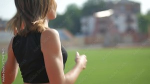 Young girl athletic runner runs on a treadmill. The athlete runs cross at the stadium. Macro shooting legs, face, body. A pretty skinny woman running.